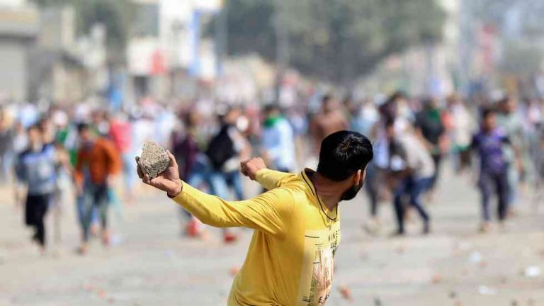 A man throws a stone at rival demonstrators during a clash over a new ...